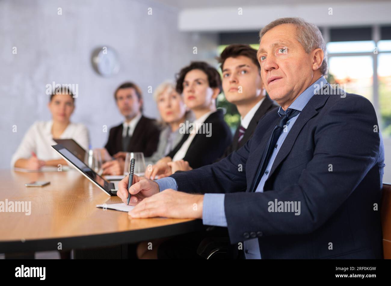 Concentrated young adult old office workers sitting around the table ...