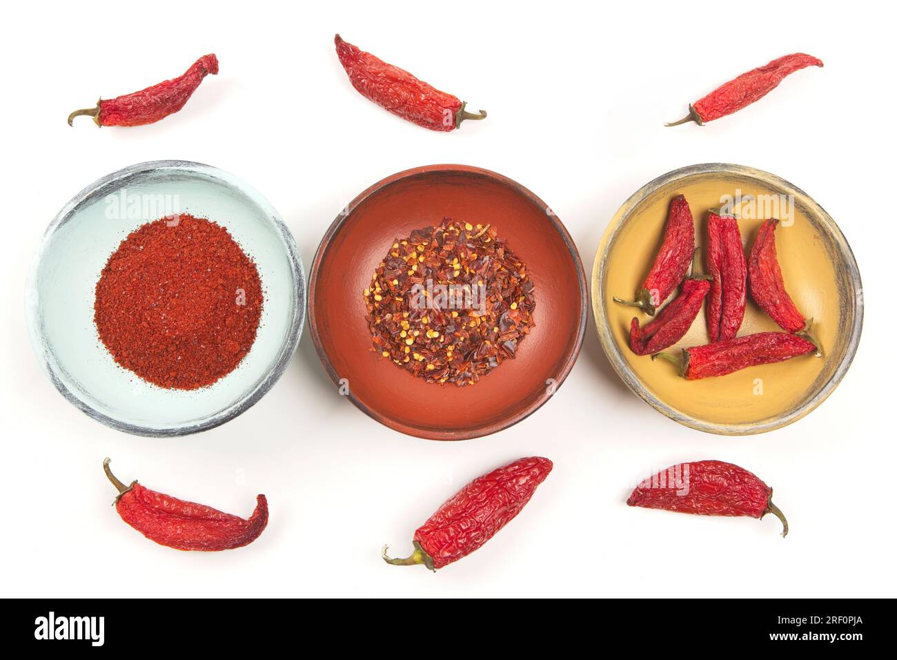A flatlay photo of wooden bowls with whole peppers, red pepper powder ...