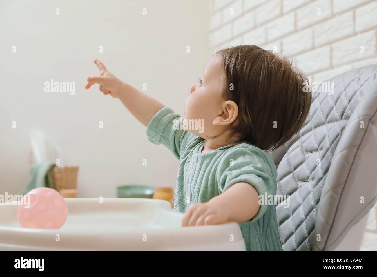 Cute little baby pointing at something in high chair indoors Stock ...