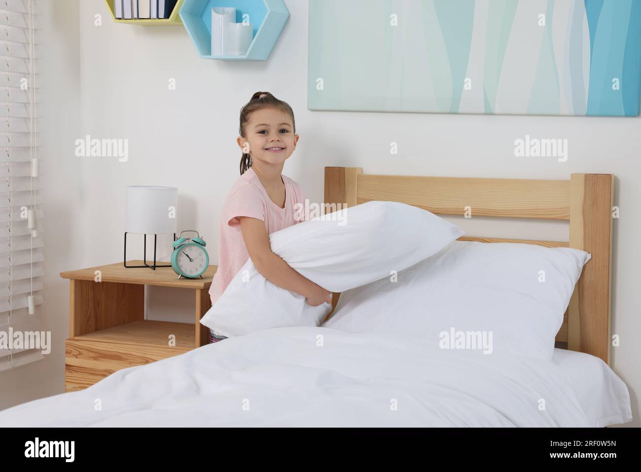 Cute girl changing bed linens in children room Stock Photo - Alamy