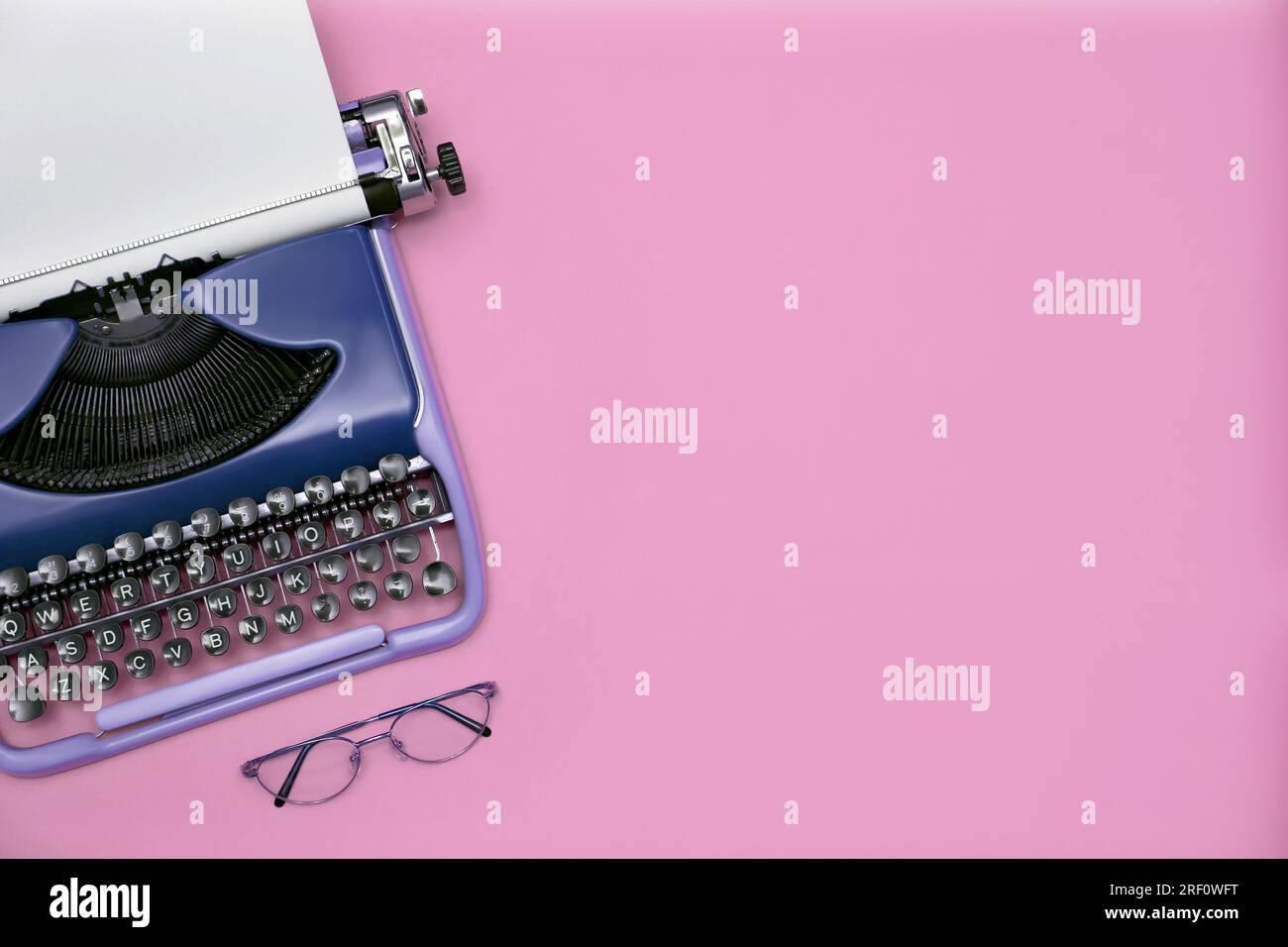 Copywriter. Vintage typewriter and eyeglasses on pink background, top ...