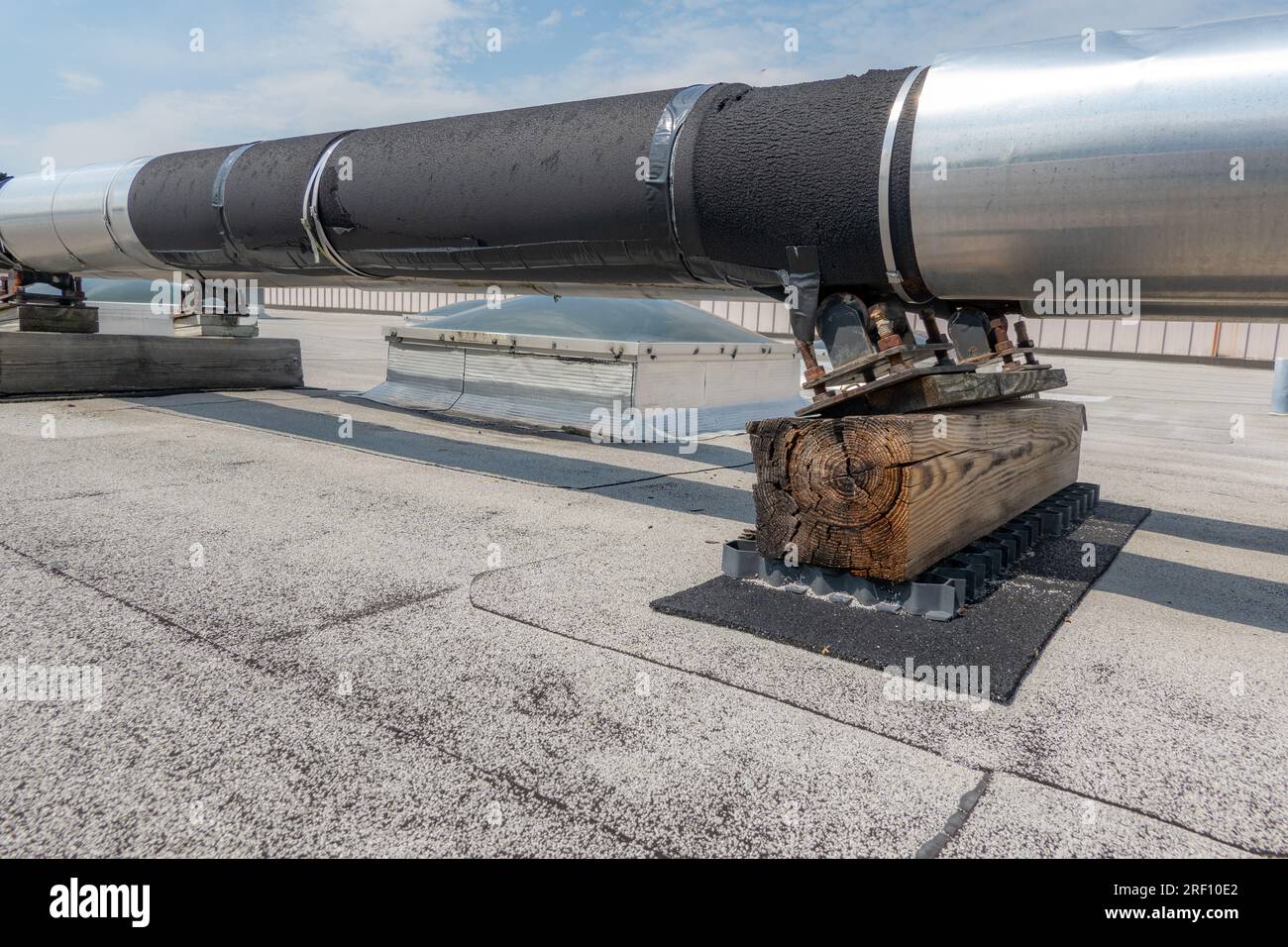 Roof mounted industrial insulated HVAC pipes on gray roof and wooden ...