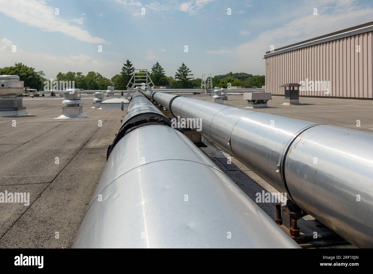 Roof mounted industrial insulated HVAC pipes on gray roof and wooden ...