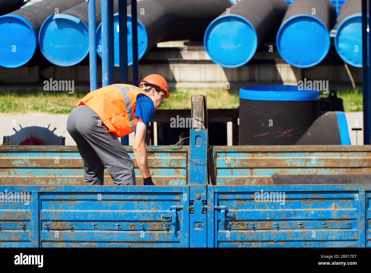 Slinger in orange hard hat and construction vest works outside on ...