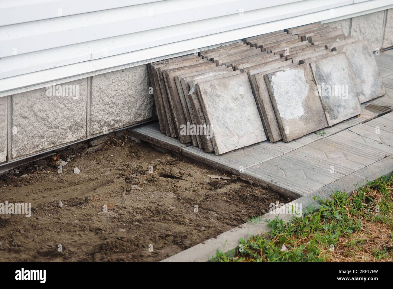 Facing concrete tiles lie on ground in stack. Replacing building ...