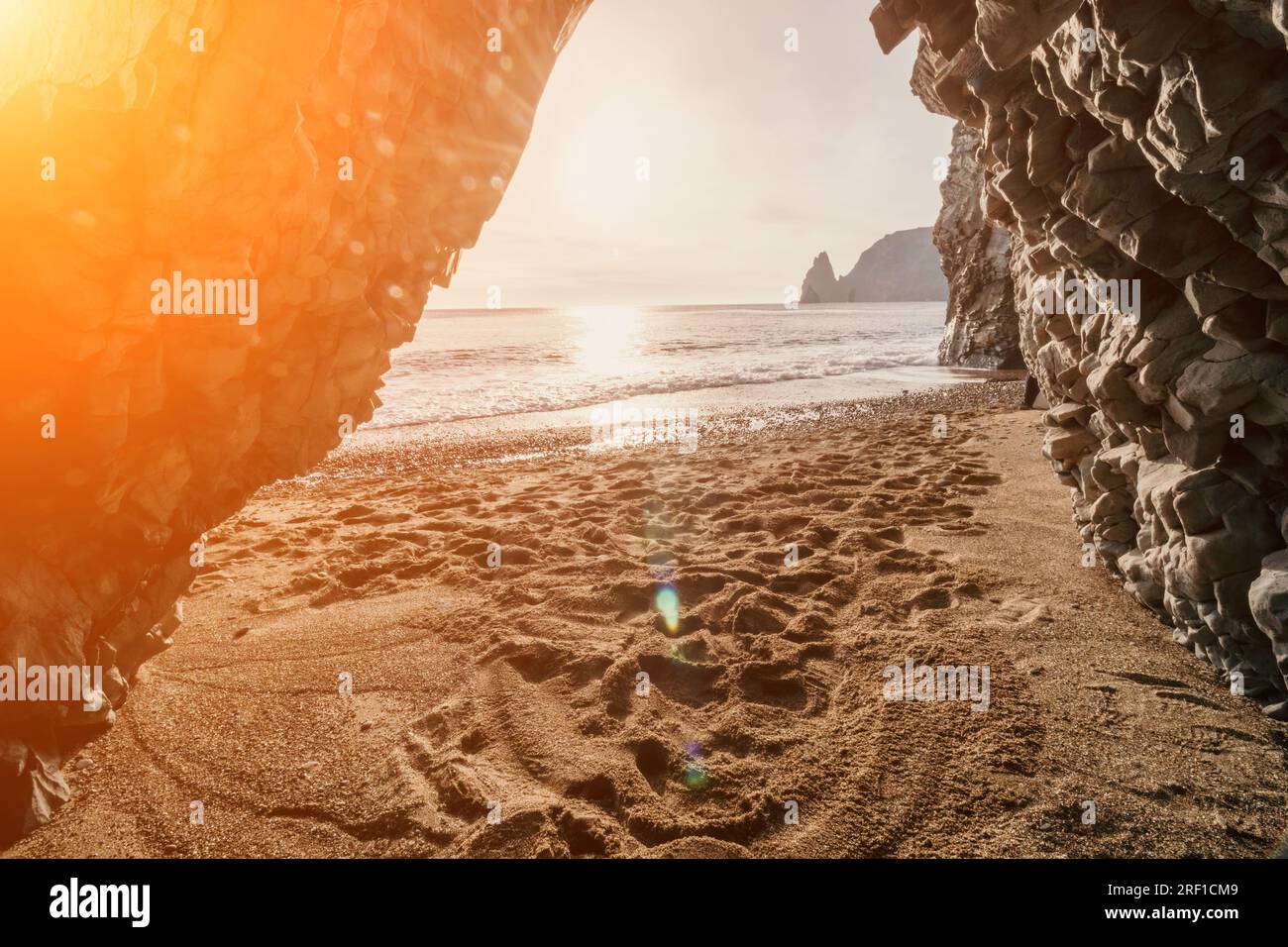 sunset seascape, captured from a rocky volcanic cave, view of the beach ...