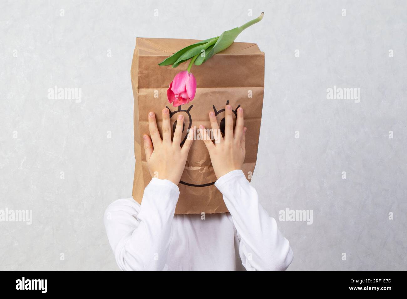 A paper bag with a painted smiling face on the child's head. The ...