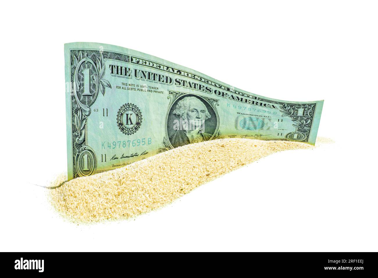 Single one-dollar bill rests amidst a pile of fine sand on a clean ...