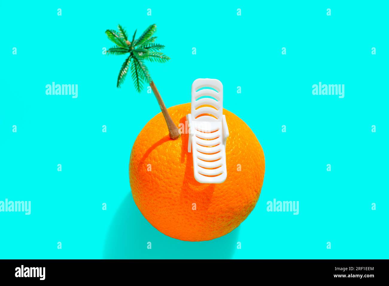 Orange fruit with a toy palm tree and miniature lounge chair atop ...
