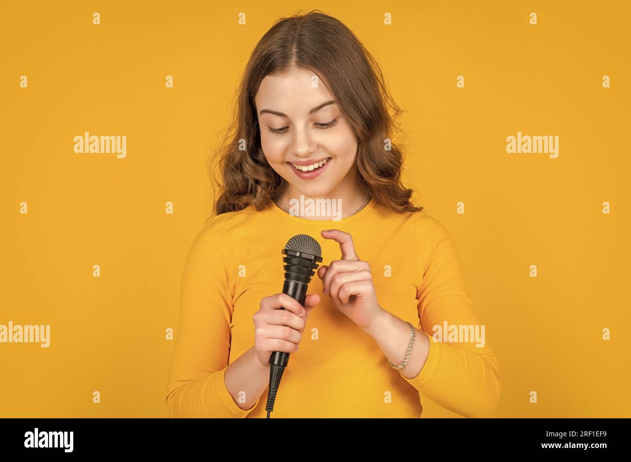 happy teen girl check mic on yellow background Stock Photo - Alamy