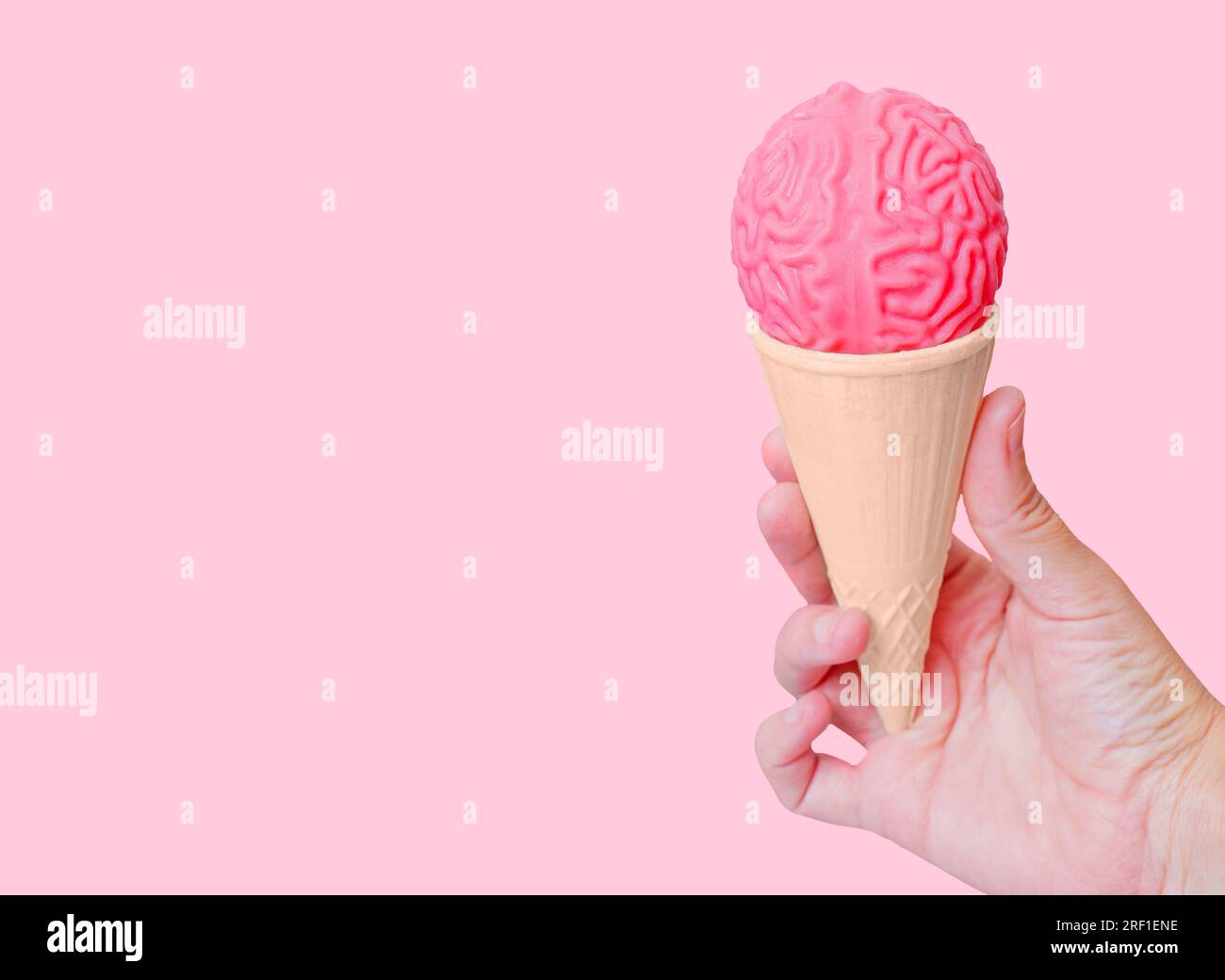 Hand holding a waffle cone filled with a human brain model isolated on ...