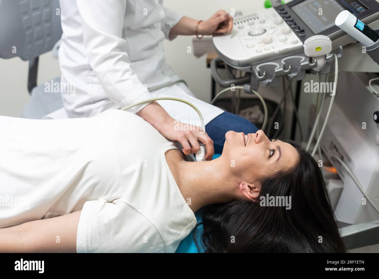 Woman endocrinologist making ultrasonography to a female patient in an ...