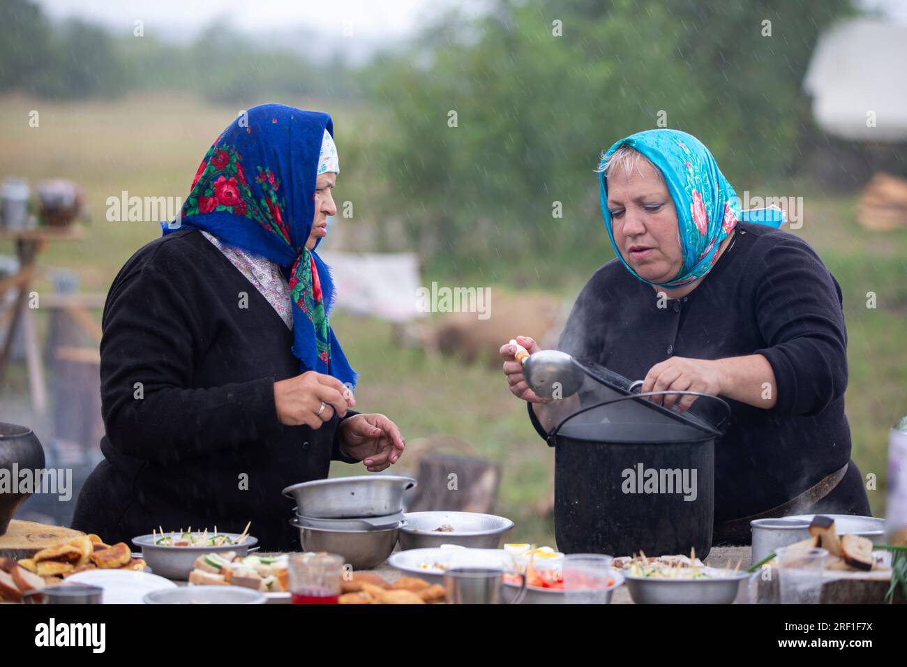 Refugee women and men prepare food outdoors in a refugee camp Stock ...