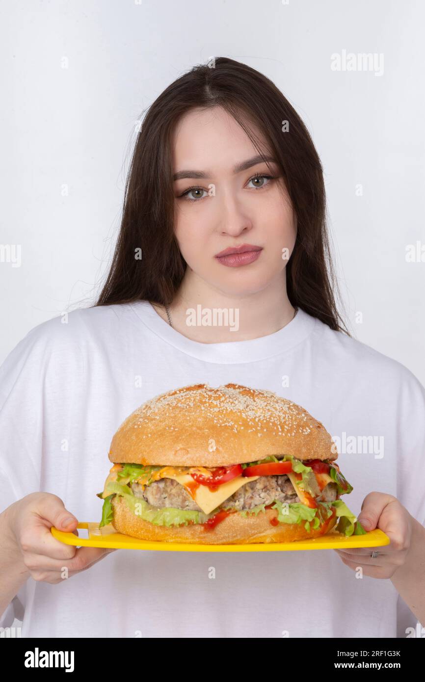 A woman is holding a big barbecue hamburger sandwich on the background ...