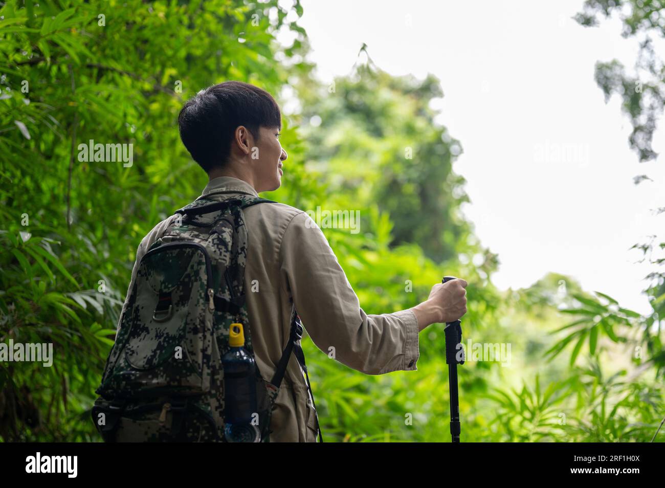 Back view of an active and happy young Asian male hiker with a backpack ...