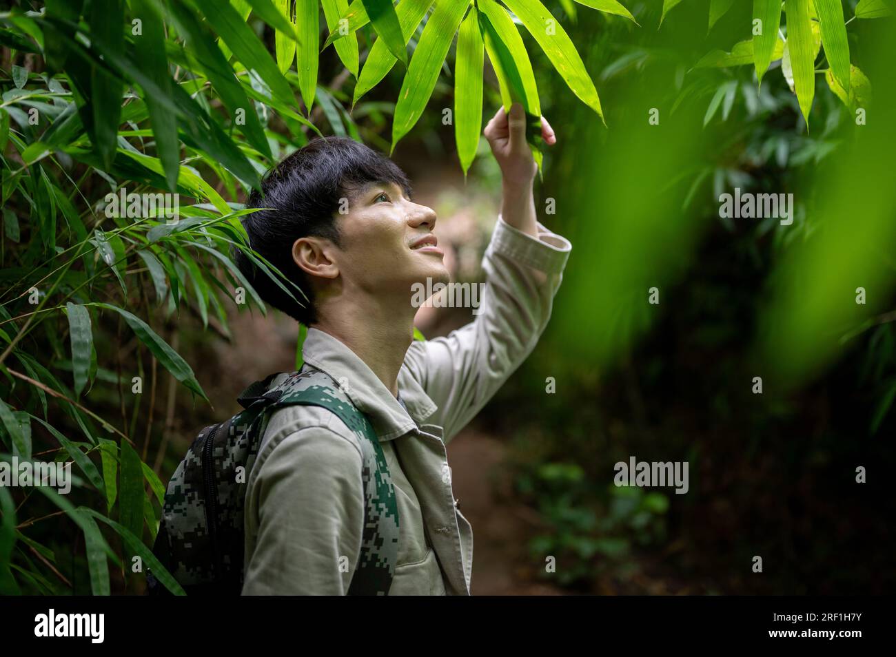 A happy and relaxed Asian male traveler enjoys nature and exploring the ...