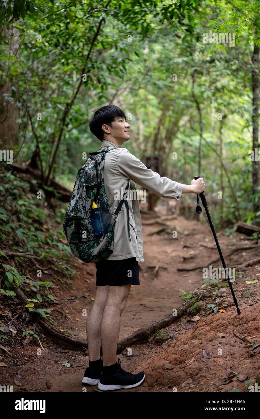 A portrait of a handsome and happy Asian male hiker with a backpack and ...