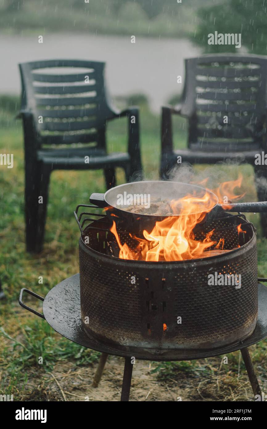 Man cooking fish on fire in nature, camping outdoors Stock Photo - Alamy