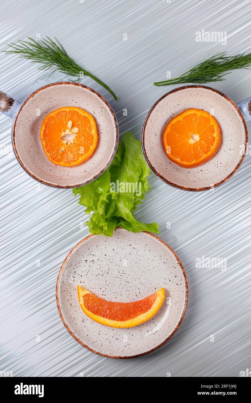 Ceramic dishes and an orange slice are folded in the form of a human ...
