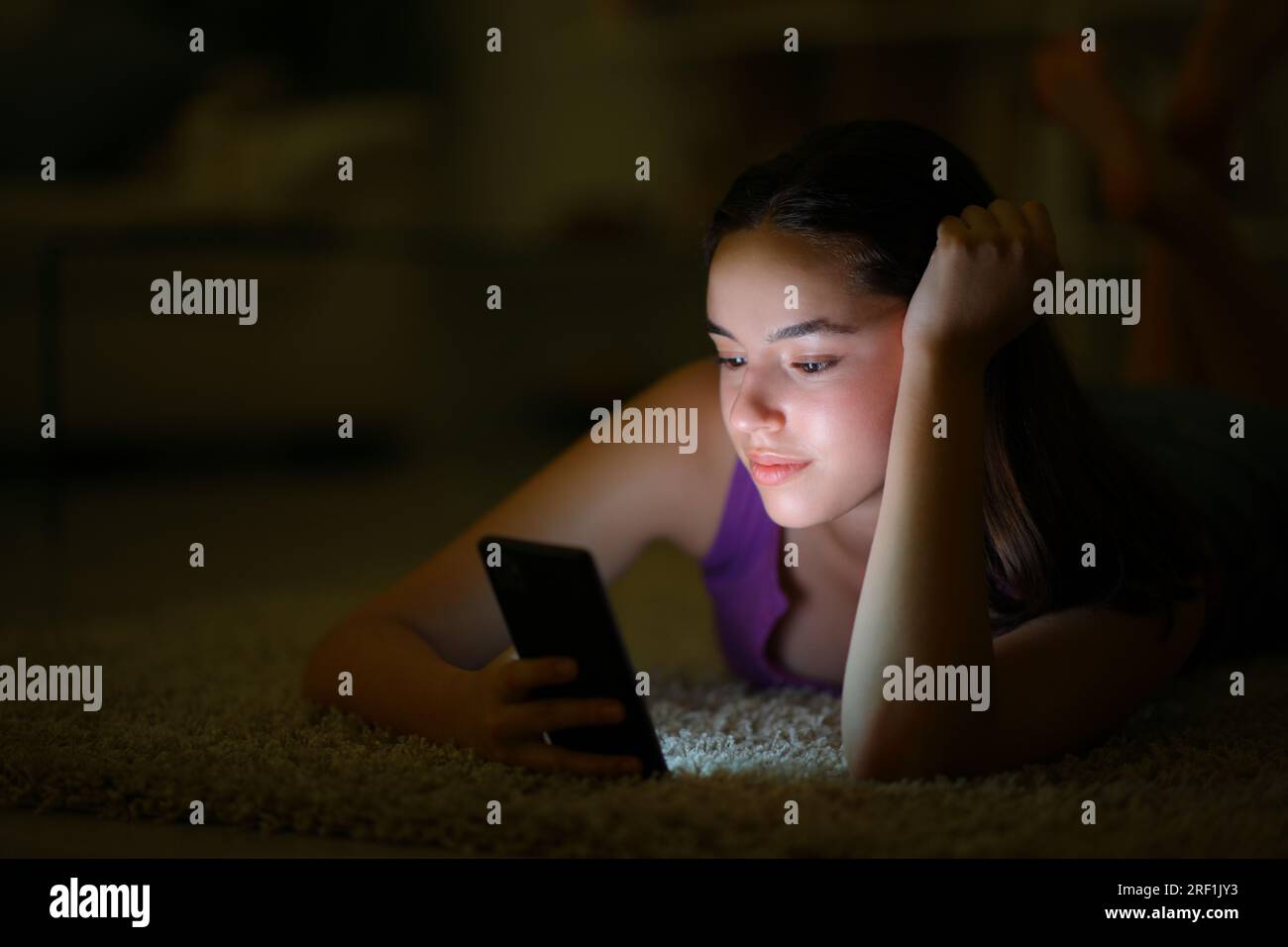 Woman in the night using phone lying on the floor at home Stock Photo ...
