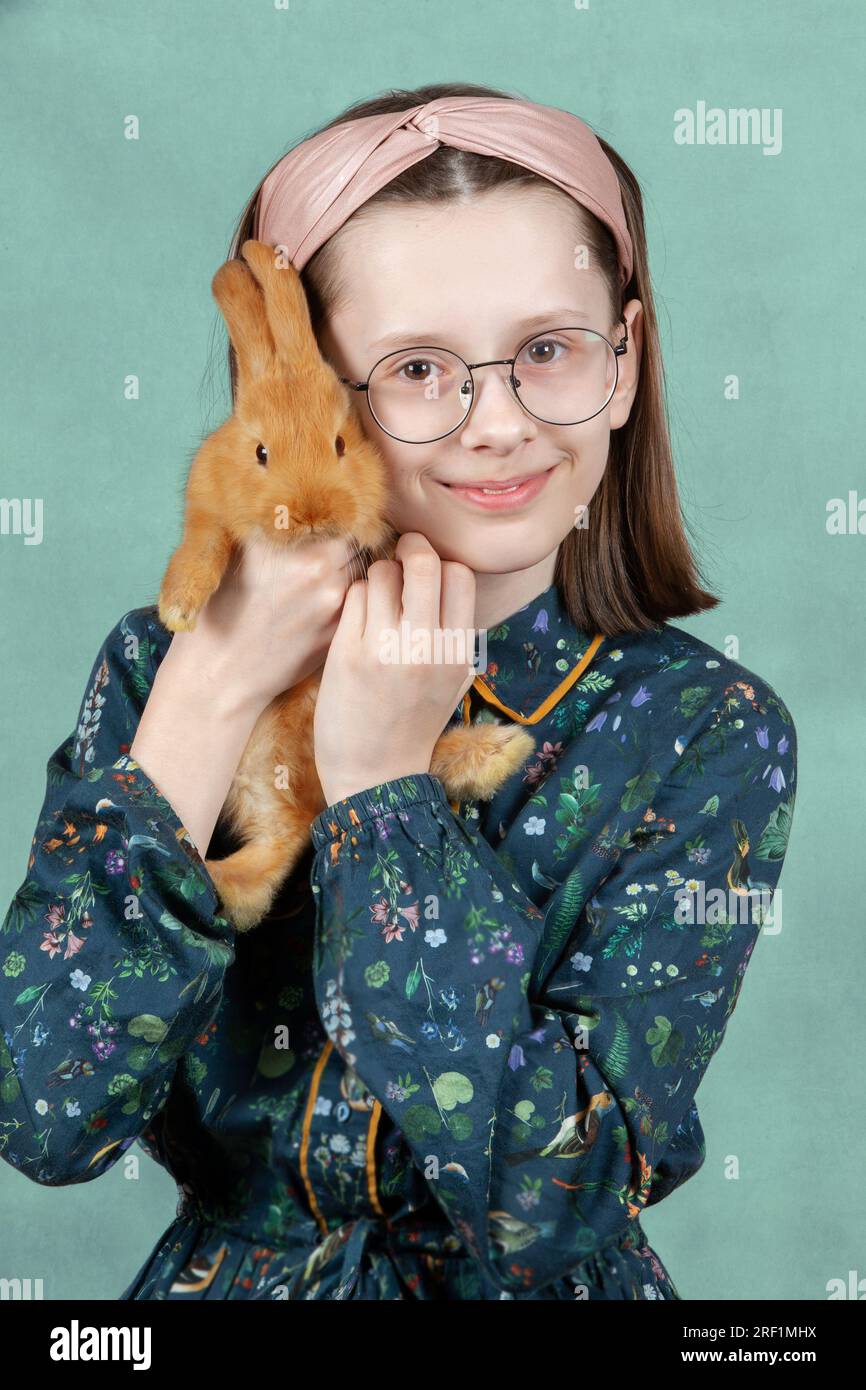 Studio portrait of a cute girl with a red hare Stock Photo - Alamy