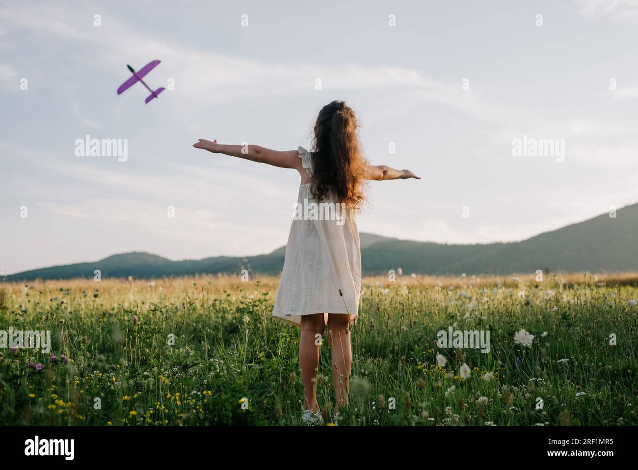 Child playing with airplane. Happy little girl launching toy plane ...