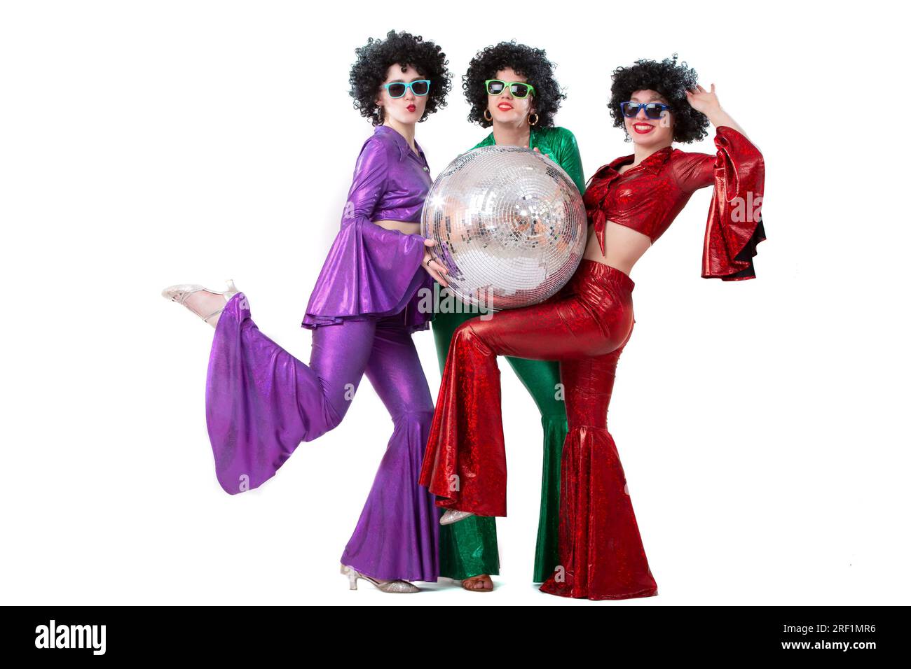 A group of girls in multi-colored disco-style costumes pose on a white ...