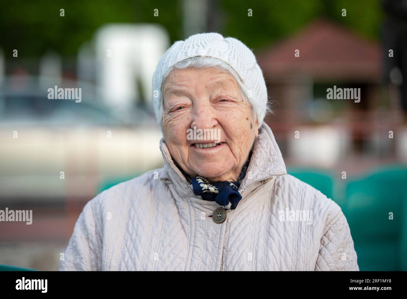 Elderly woman with wrinkles in a knitted hat, smiling, looking at the ...