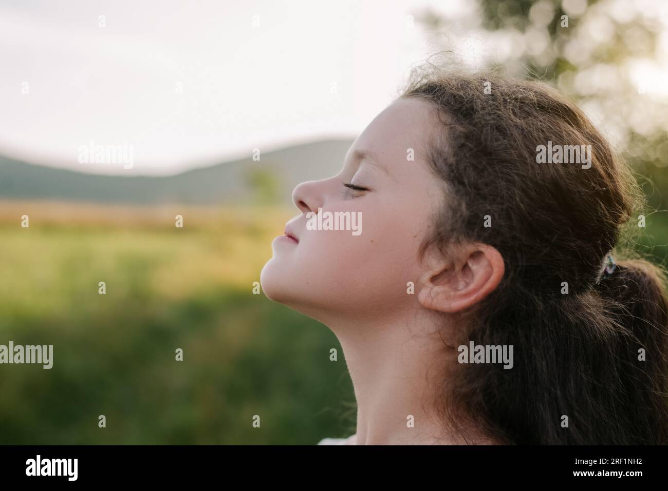 Closeup of relaxed little child with close eyes in outdoors breathe ...