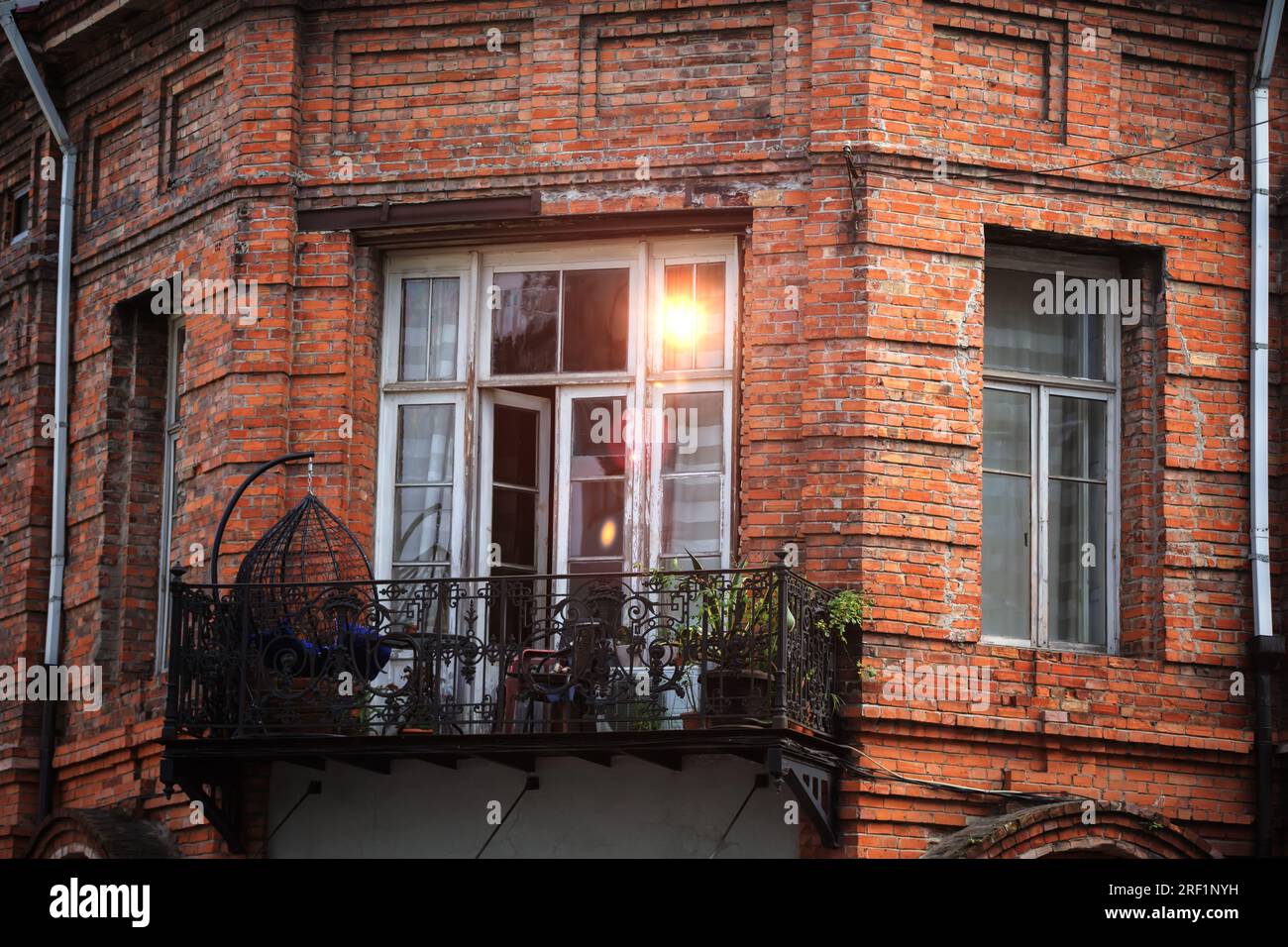 Windows with a balcony in an old brick building with sun reflection ...