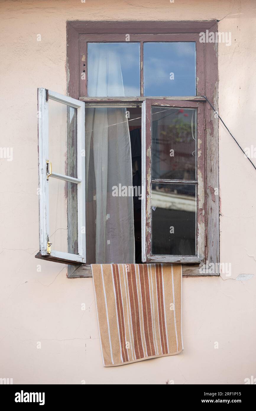 A towel dries on an old wooden window with a crooked frame. Live in a ...