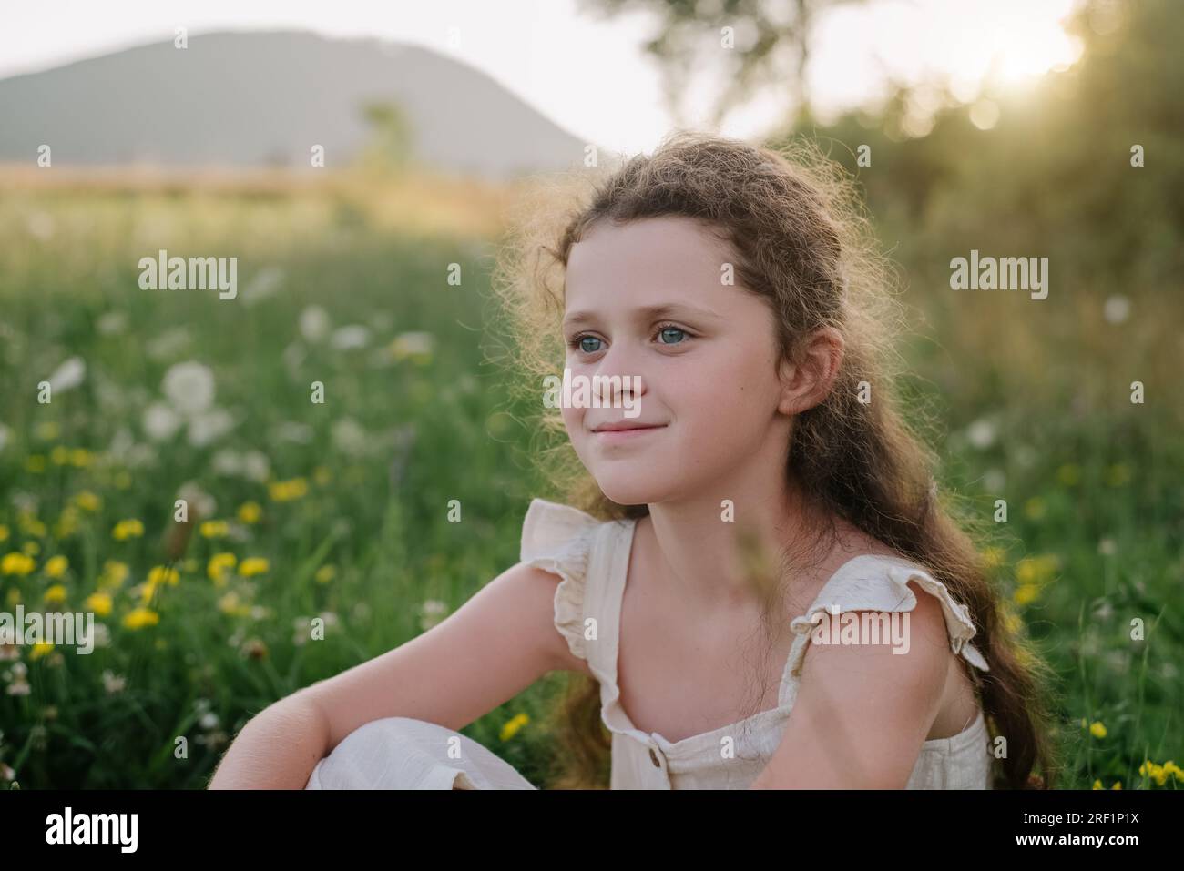Portrait Of Happy Preteen Girl Sitting On Green Grass Outdoor Enjoying