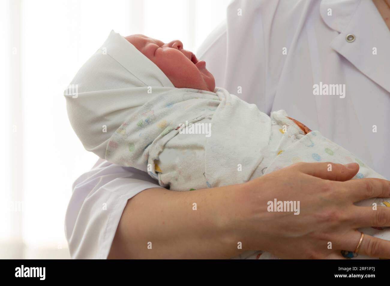 The doctor's hands hold a newborn baby wrapped in a diaper Stock Photo ...
