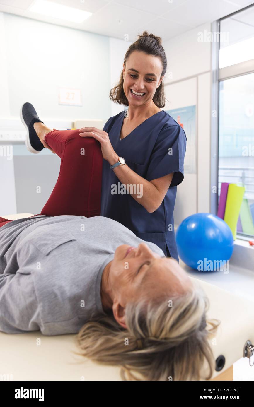 Caucasian female physiotherapist and senior woman stretching leg at ...