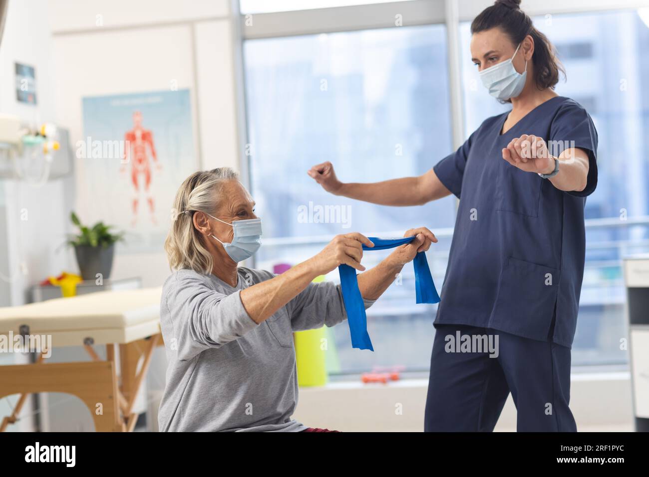 Caucasian physiotherapist and senior woman with face masks using ...