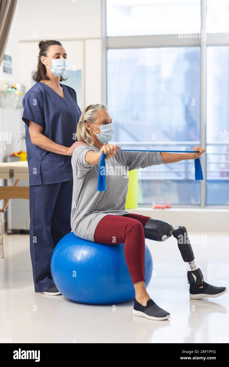 Caucasian physiotherapist and senior woman with artificial leg with ...