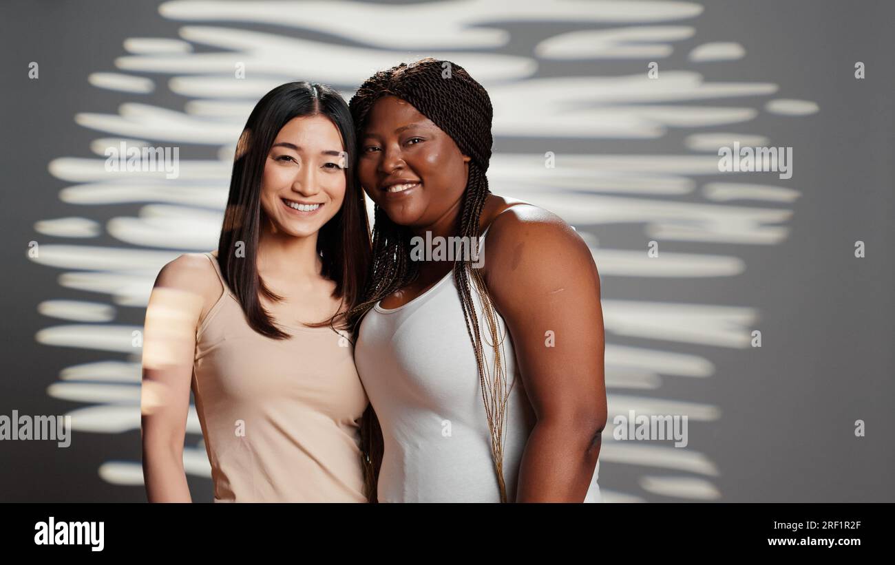 Flawless confident diverse girls posing together on camera, showing ...