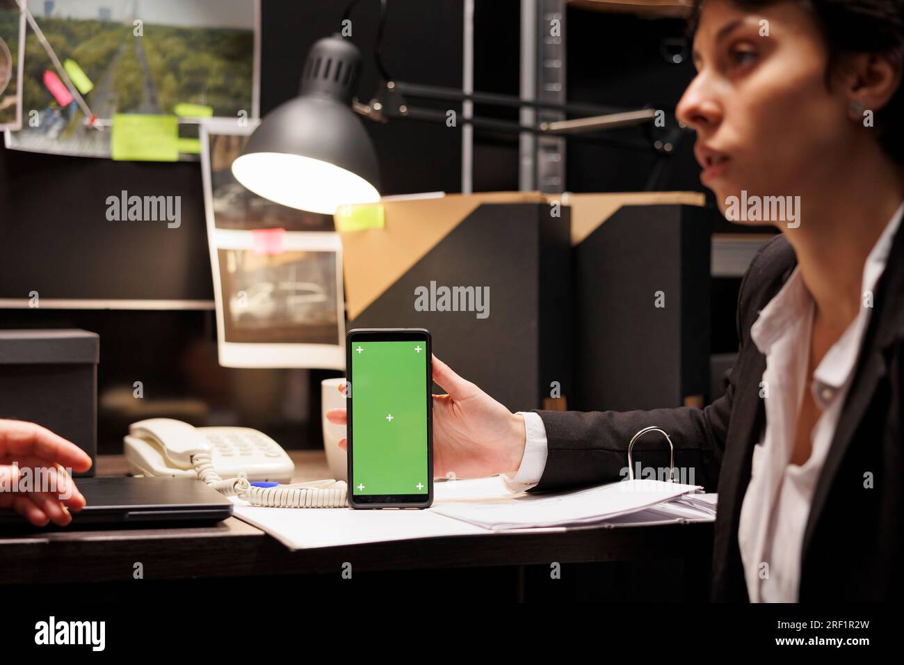 Private detective holding smartphone with green screen mock up display ...