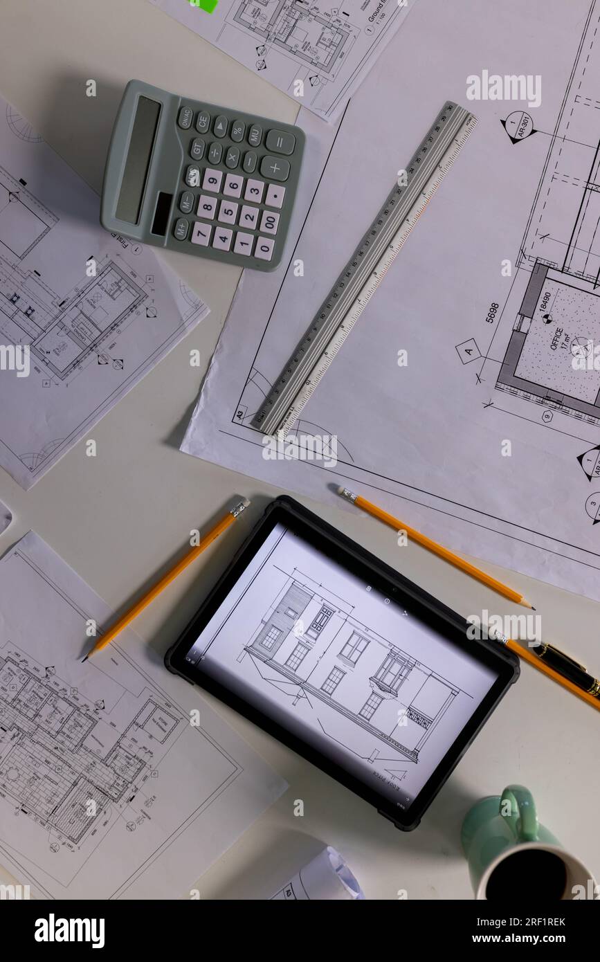Overhead view of desk with architectural blueprints, tablet, calculator ...