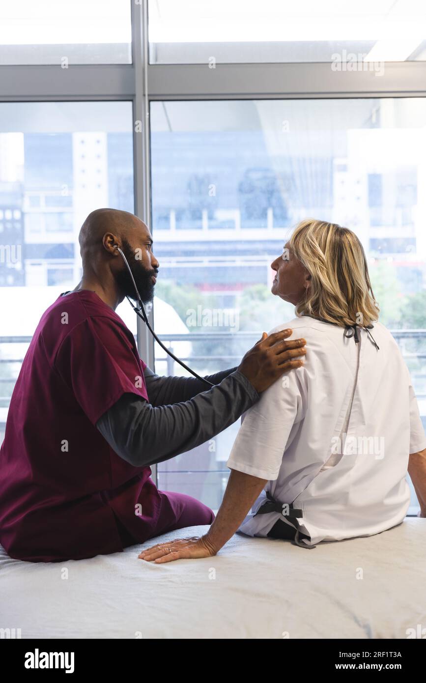 African american male doctor examining senior female caucasian patient ...