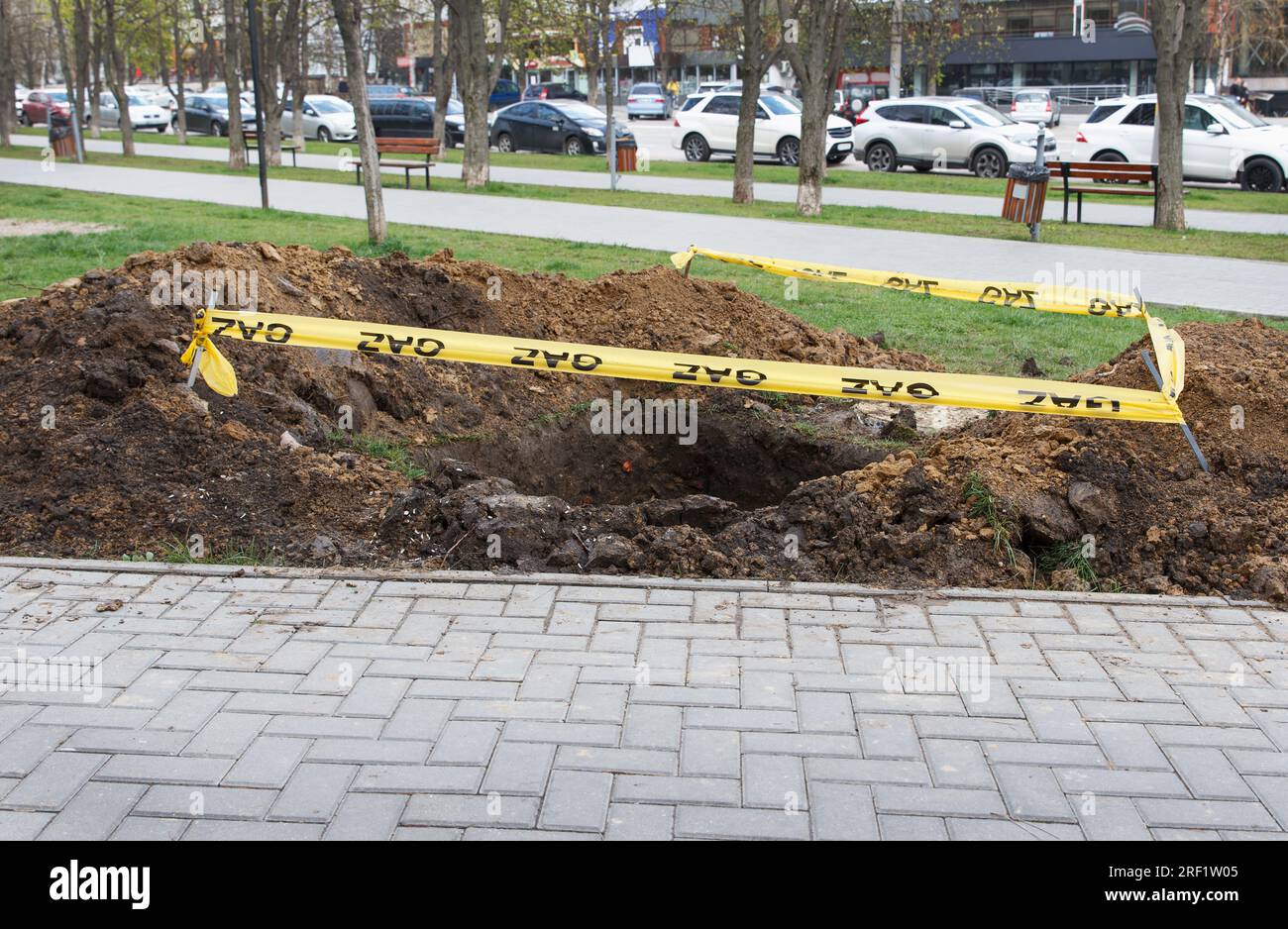 A square pit dug into the soil, next to the public sidewalk and fenced ...
