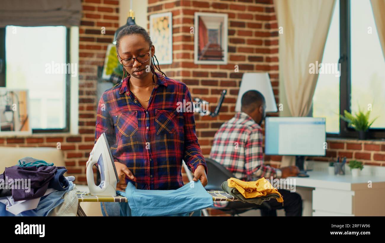 Stressed woman feeling tired ironing clothes with steam, feeling ...
