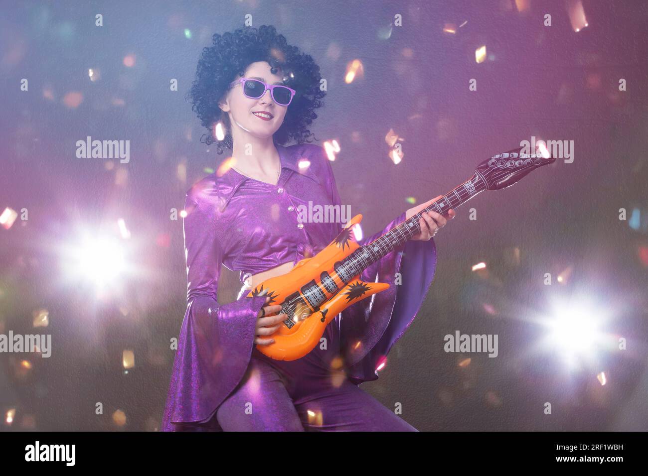 Happy girl pop singer with a toy guitar on the background of shiny ...