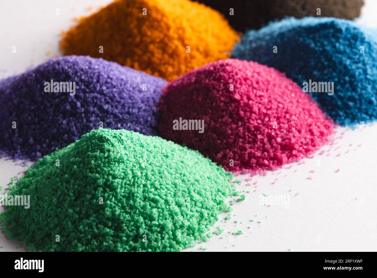 Close up of heaps of multi coloured sand and copy space on white ...