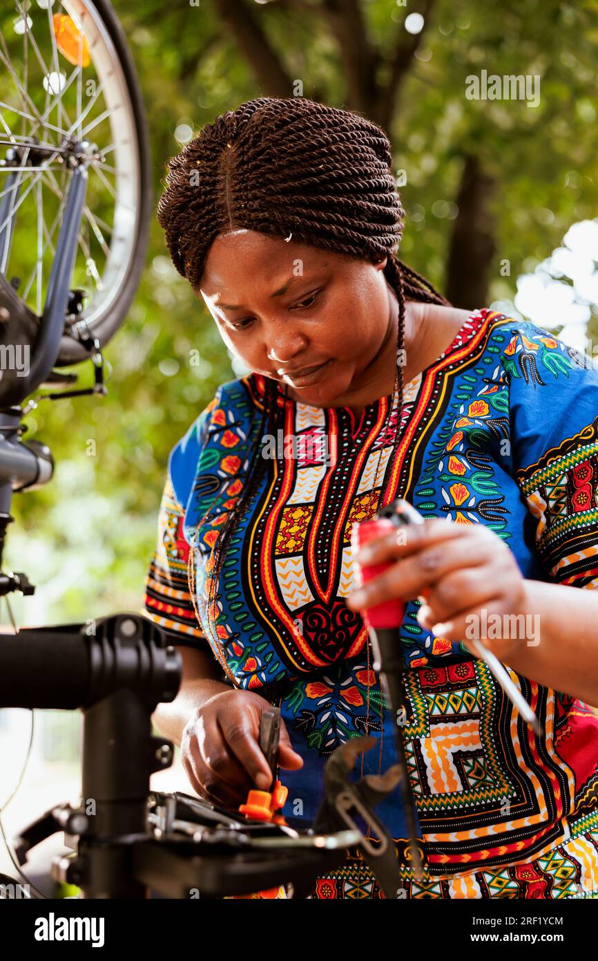 Sports-loving black woman servicing and adjusting bike components with ...