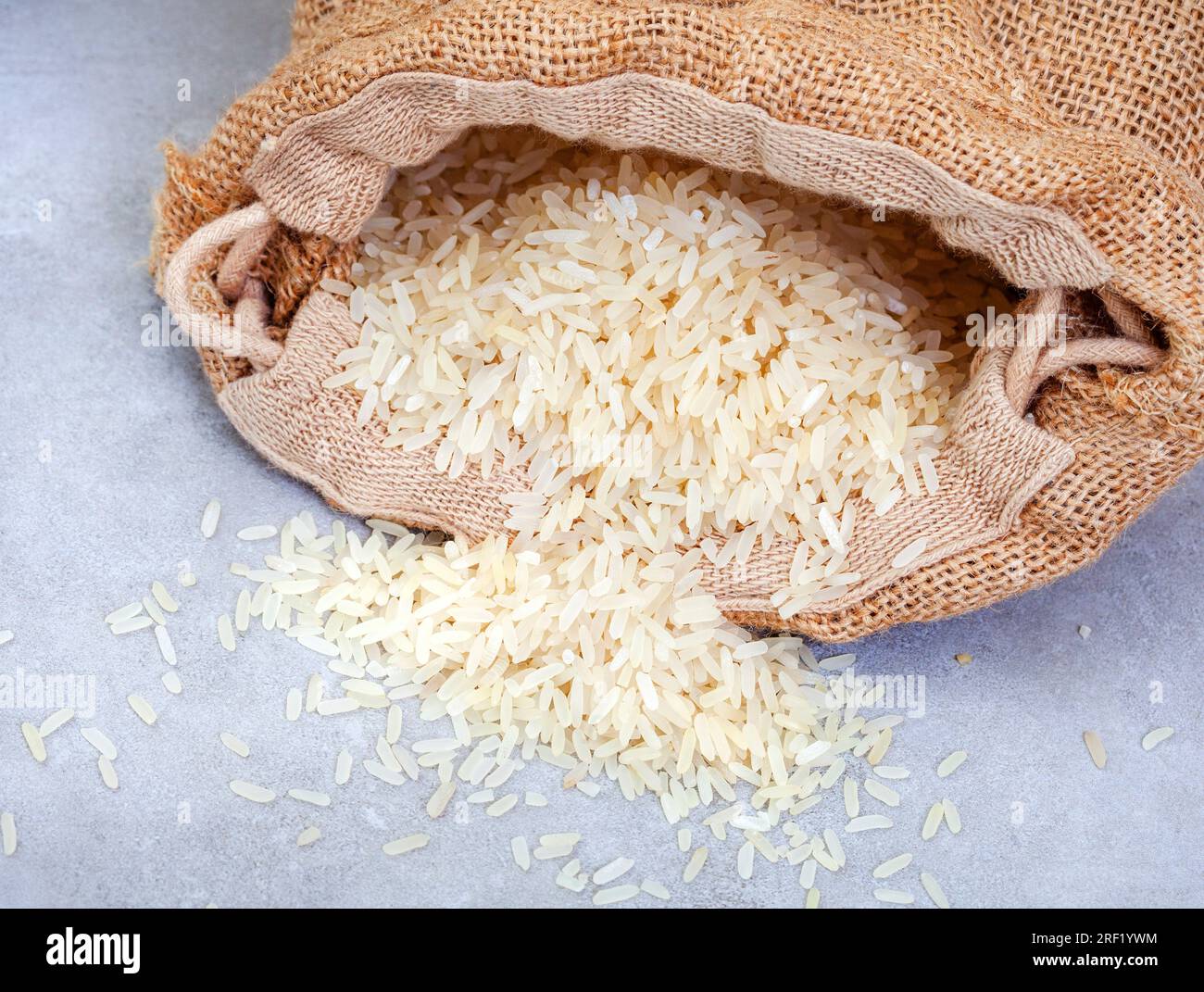 Basmati rice pouring from a burlap sack on grey Stock Photo - Alamy