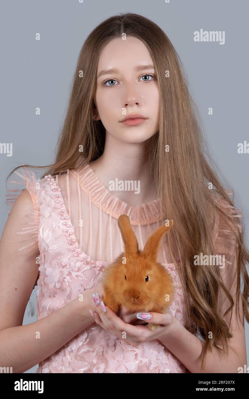 Portrait of a teenager girl with long blond hair and a red rabbit on a ...