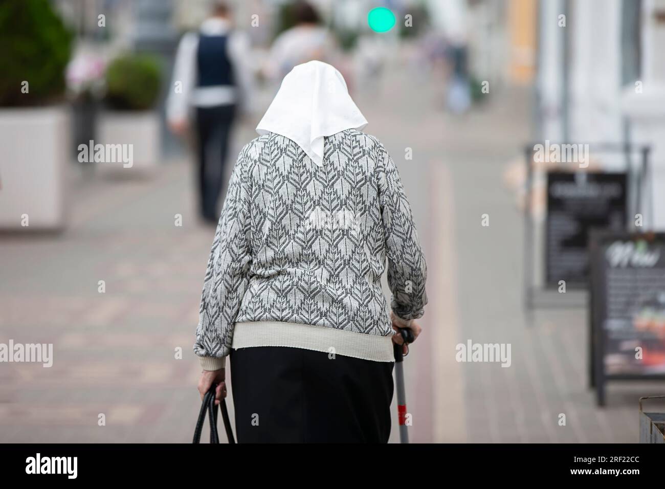 An old, hunched-over grandmother in a handkerchief with a stick and a ...