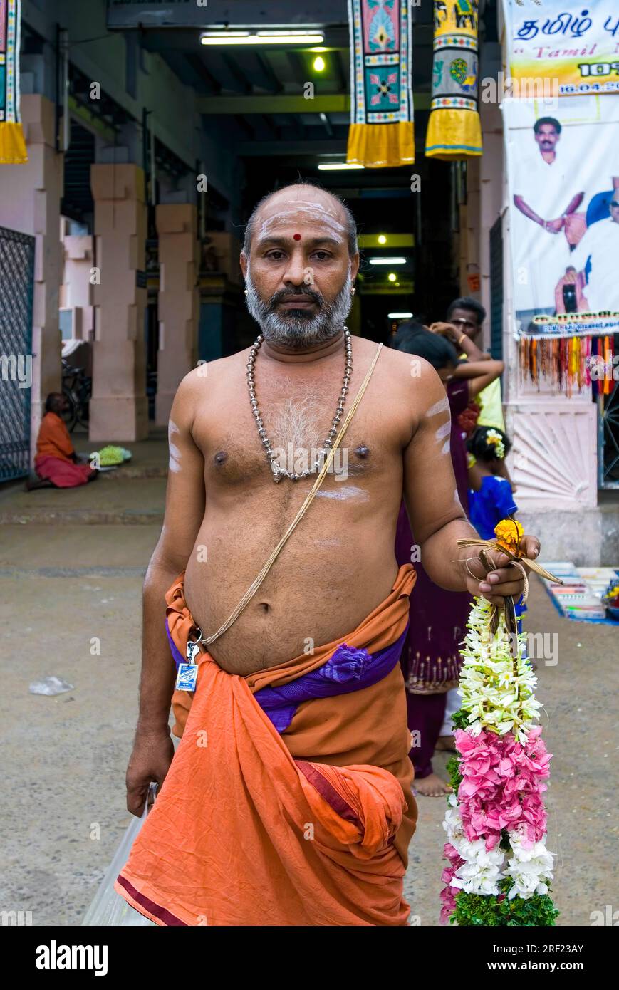 Priest standing with garlands in front of Swaminatha Swamy God Murugan ...