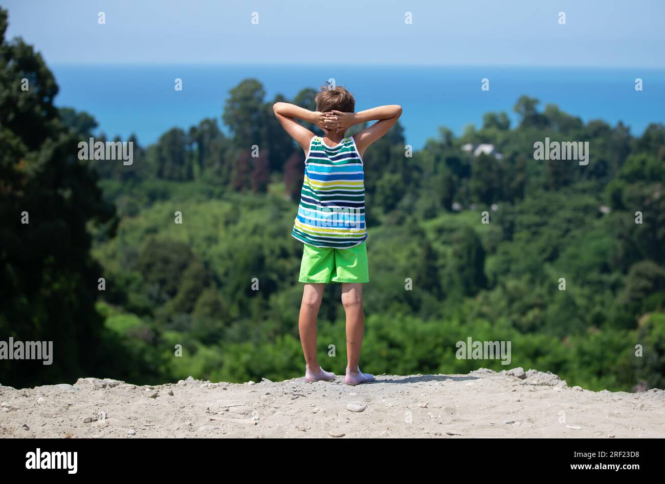The boy stands with his hands folded in front of his head and admires ...